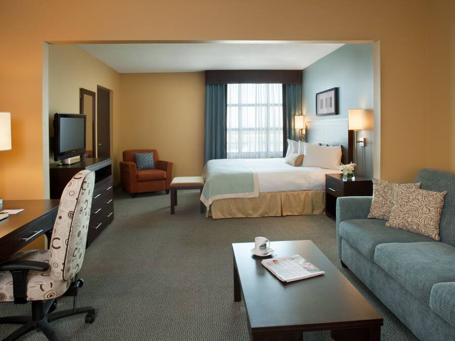Quarto de hotel com escrivaninha, cadeira, cama e sofá.