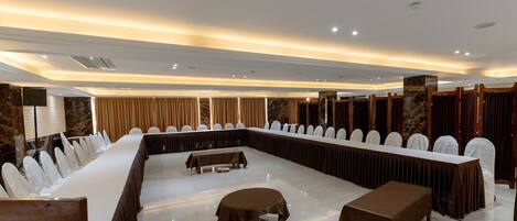 Uma sala de conferências com uma mesa comprida, mesas redondas e cadeiras.