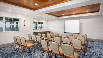 Uma sala de conferências com uma tela grande, teto de madeira e carpete azul.