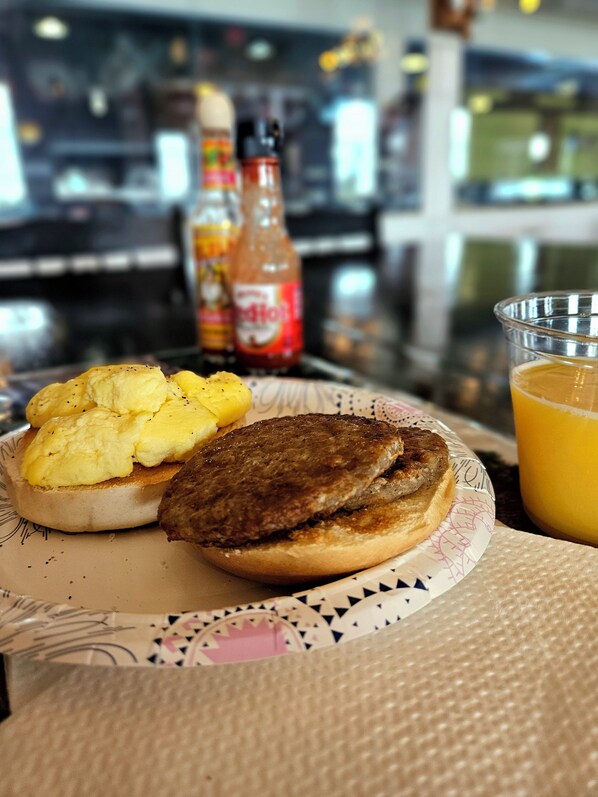 Prato de café da manhã com ovos, uma salsicha e um copo de suco de laranja.