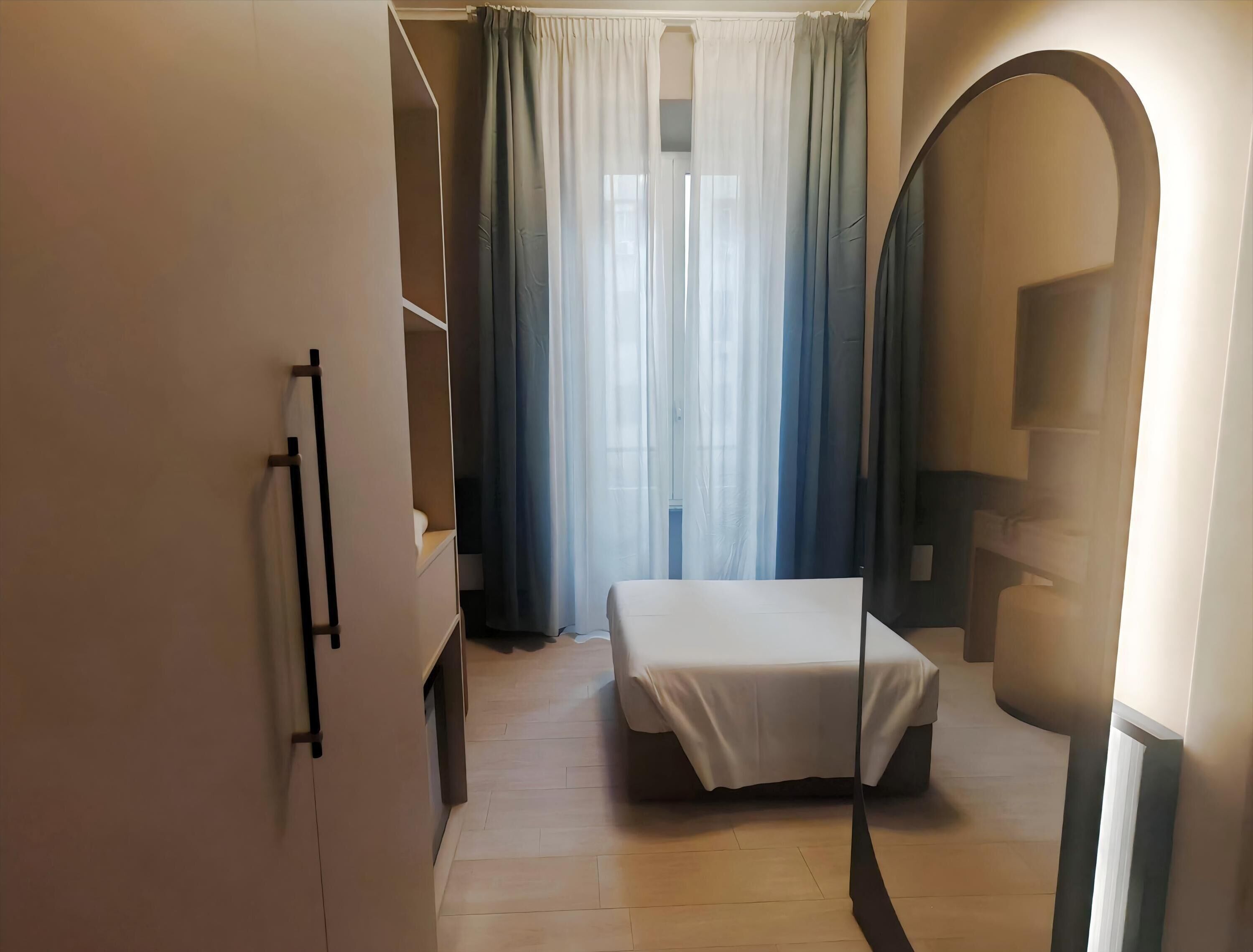 Quarto com cama, guarda-roupa e espelho.