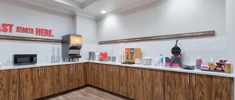 Cozinha moderna com micro-ondas, cafeteira e um letreiro que diz 'STARTS HERE'.