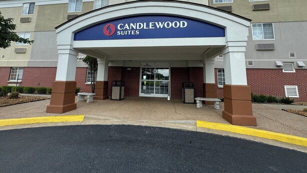 Entrada de um hotel com uma placa indicando "Candlewood Suites".