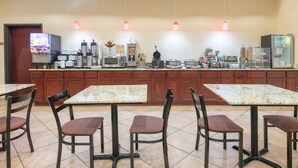 Uma cozinha de hotel com bancadas de granito, eletrodomésticos de aço inoxidável e um espaço para café.