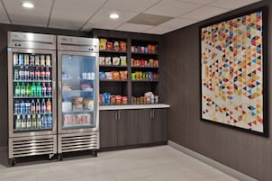 Uma área de distribuição automática com dois dispensadores de bebidas e uma prateleira com lanches.