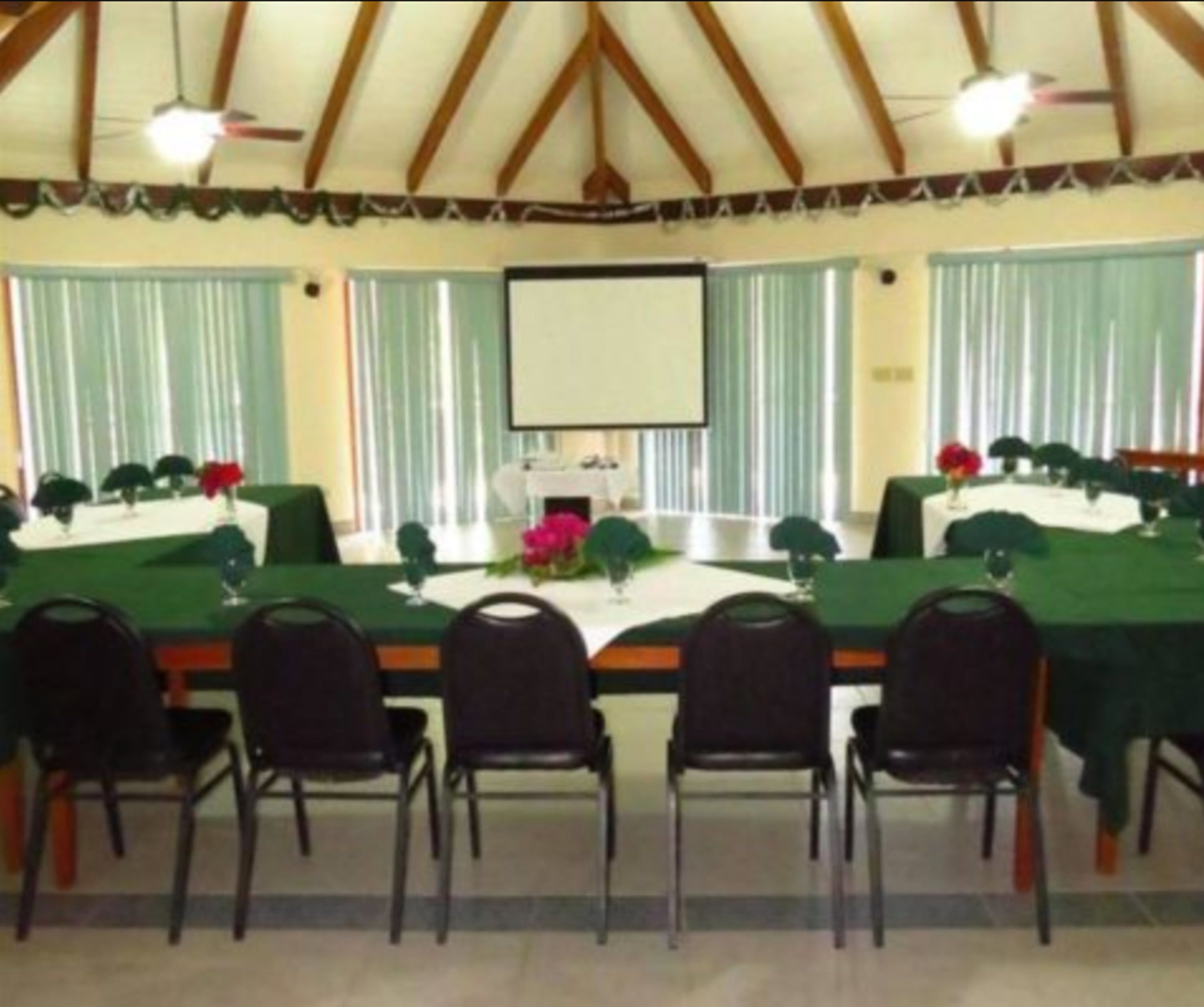 Uma sala de conferências com uma mesa comprida, cadeiras, uma tela de projetor e uma lareira.