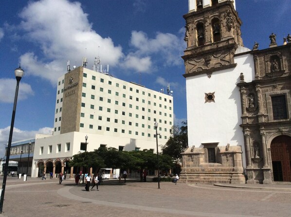 Um edifício histórico com uma torre de sino e um edifício moderno branco com uma grade de janelas.