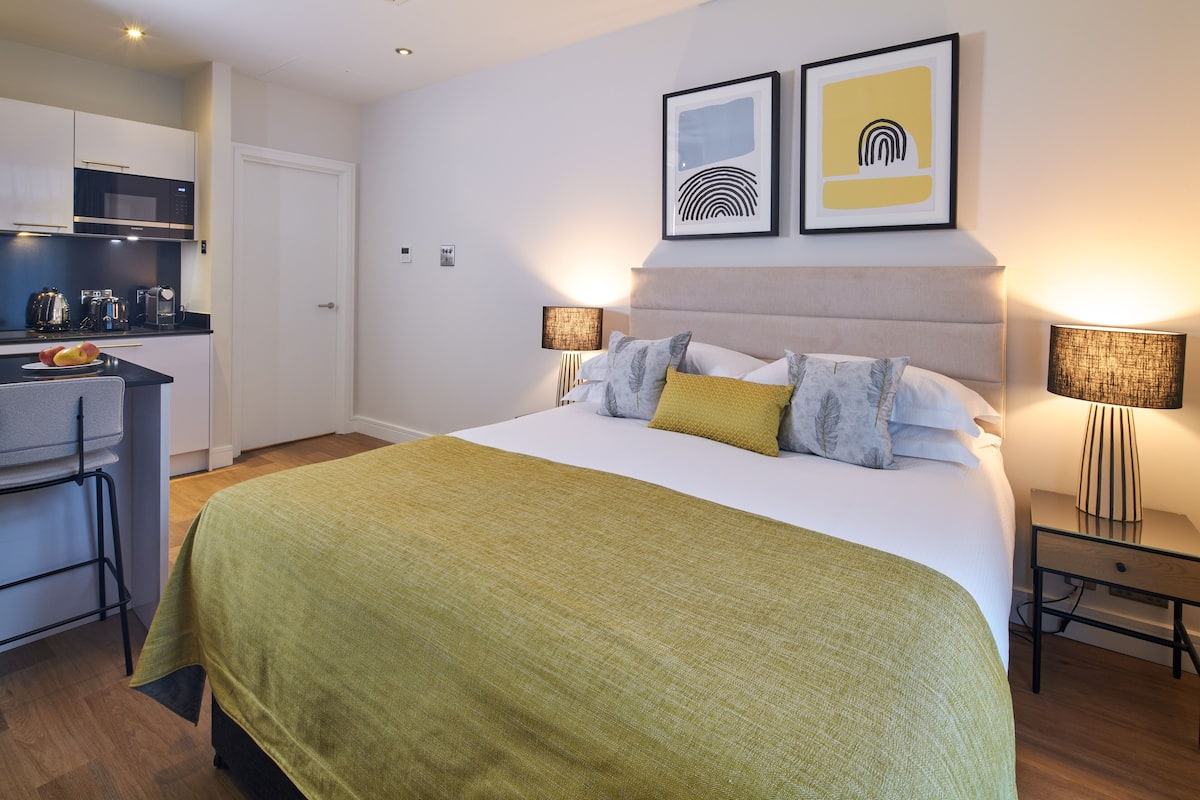 Quarto com cama, abajures e mesa de cabeceira.