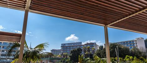 Área externa coberta com vista para um edifício de vários andares identificado como "COSTA ENCANTADA" ao fundo.