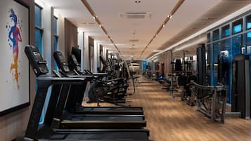 Uma academia moderna com esteiras, aparelhos de musculação e piso de madeira.