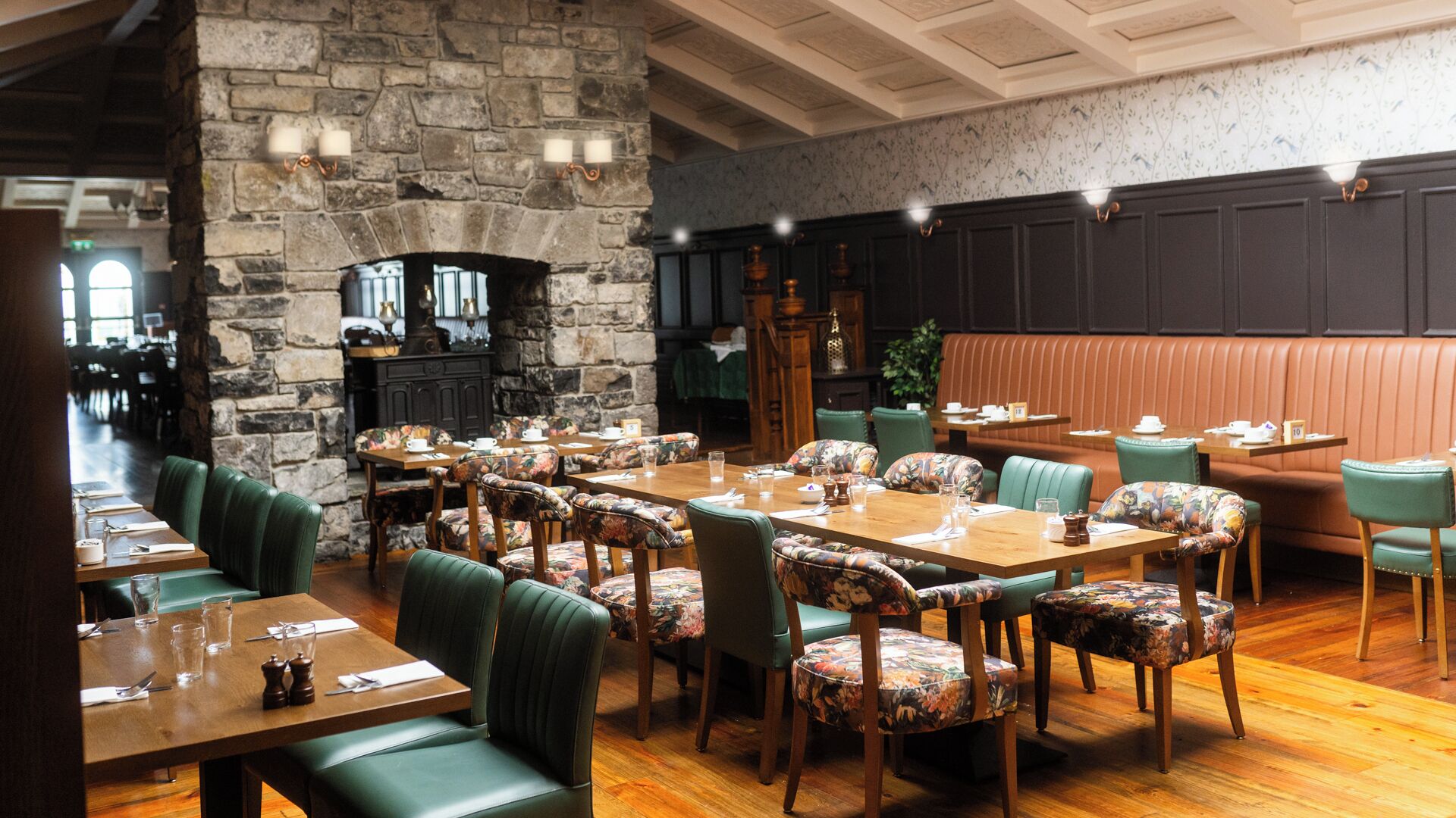 Um restaurante com mesas e cadeiras de madeira, paredes de pedra e uma lareira.