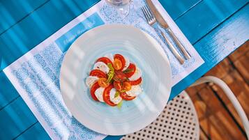 Uma salada Caprese num prato sobre uma toalha azul com um guardanapo estampado.