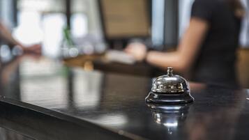 Uma área de recepção de hotel com um balcão preto e um sino de prata.