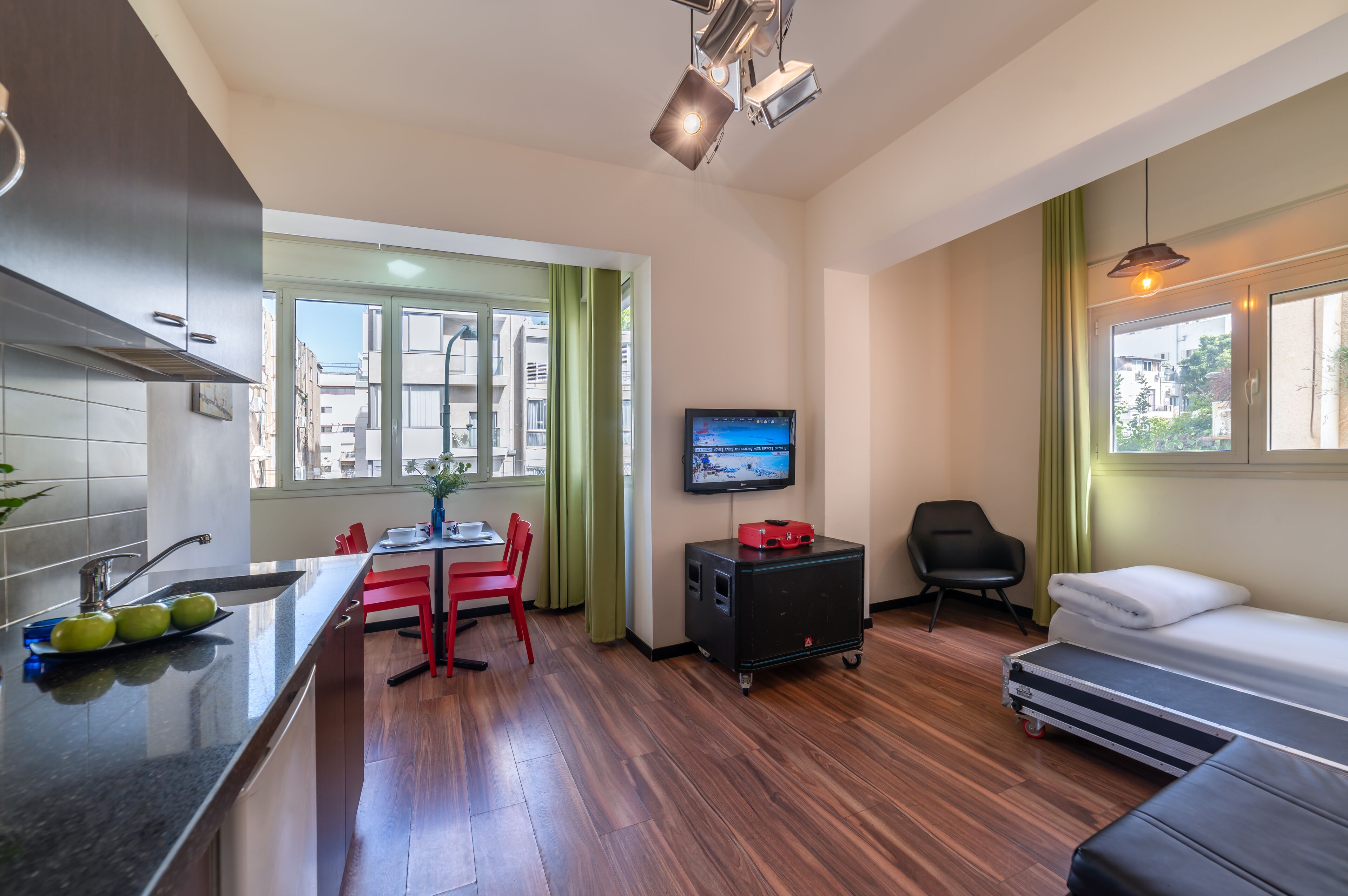 Quarto de hotel compacto com cozinha compacta, uma cama, TV e vista da cidade.