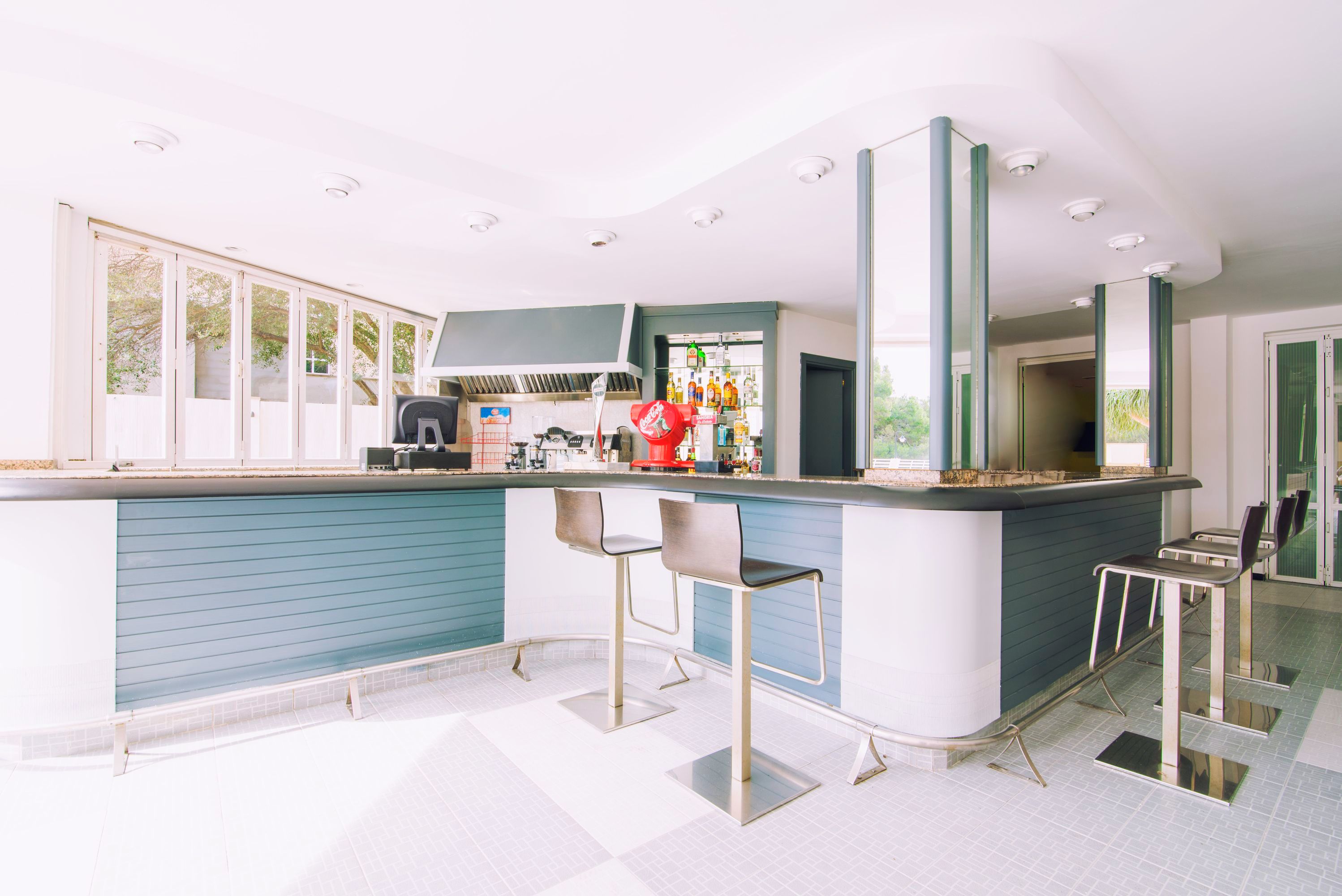 Cozinha moderna com área de bar, banquetas e vista para o exterior.