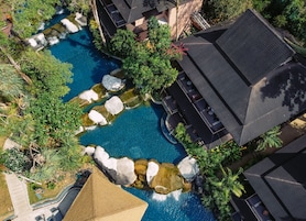 Vista aérea de um resort com piscina, formações rochosas e vegetação ao redor.