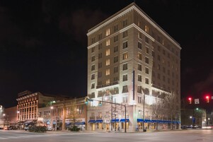 Um hotel de vários andares com estilo arquitetônico clássico, apresentando uma entrada central e diversas janelas em cada pavimento.