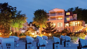 Um hotel à beira-mar com várias varandas, área de estar ao ar livre e fachada bem iluminada.