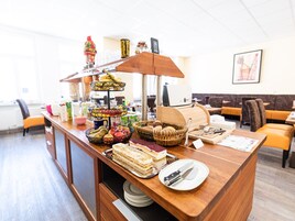 Buffet montado com diversos alimentos e uma máquina de café.