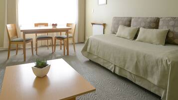 Um quarto com uma cama, uma mesa de jantar com cadeiras e uma pequena planta sobre a mesa.
