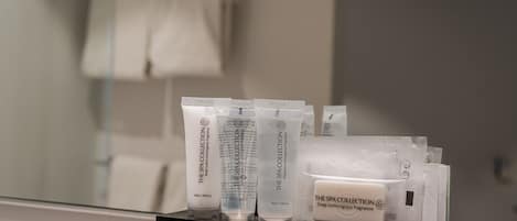 Uma bancada de banheiro com produtos de higiene pessoal da Coleção Spa, incluindo shampoo, gel de banho e sabonete.