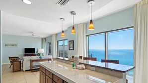 Cozinha ampla com uma ilha grande, sala de jantar com vista e sala de estar com televisão de tela plana.