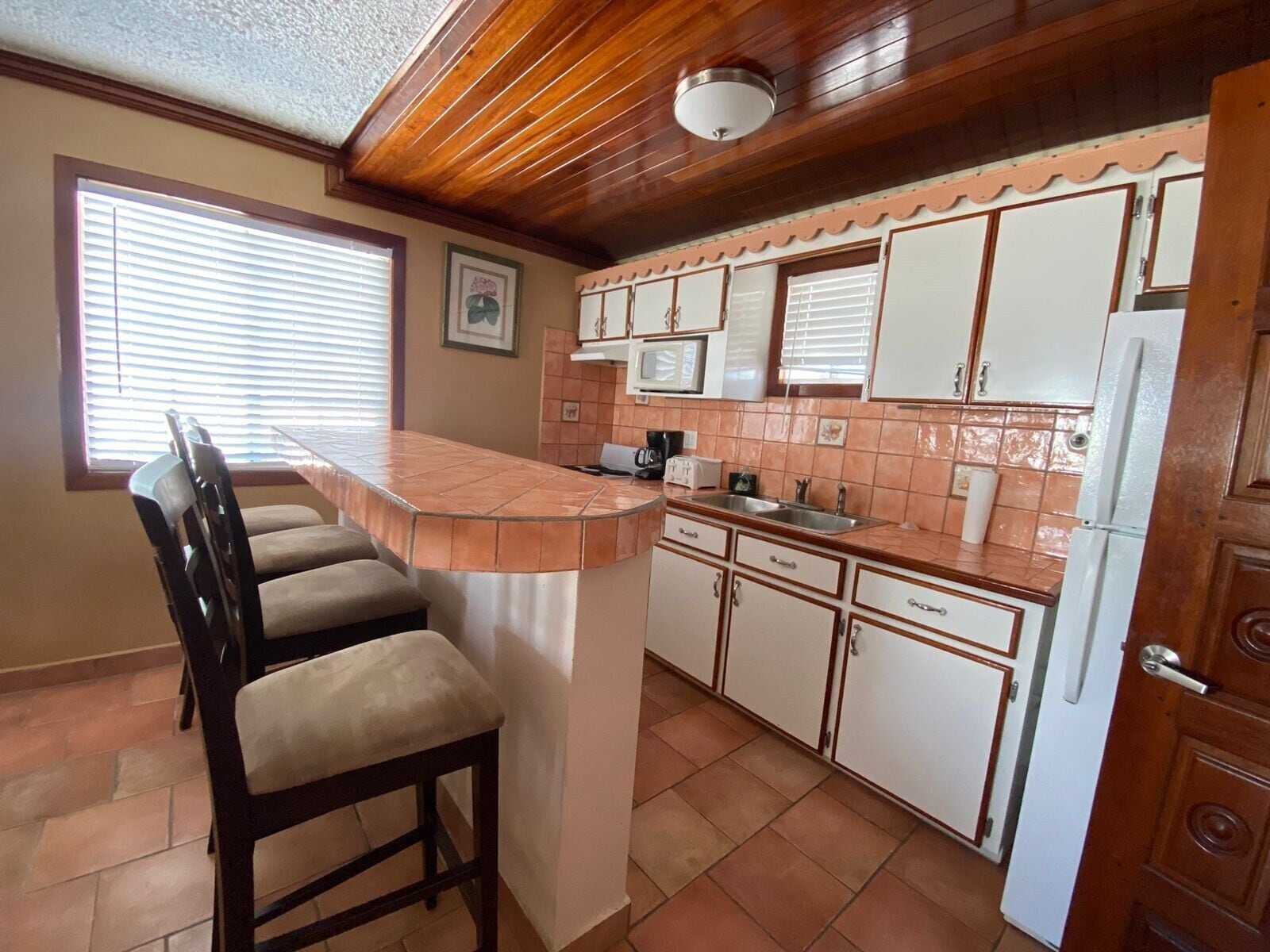 Cozinha com balcão, armários brancos e micro-ondas.