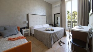 Quarto de hotel com cama, escrivaninha e varanda.