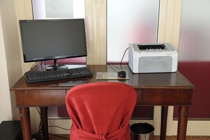 Uma mesa de madeira com monitor de computador, teclado, rato e impressora.