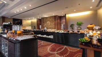 Uma área de buffet com diversas opções de comida, uma máquina de café e uma parede decorativa.