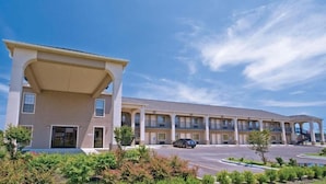 Um motel com vários andares, entrada central e varandas.