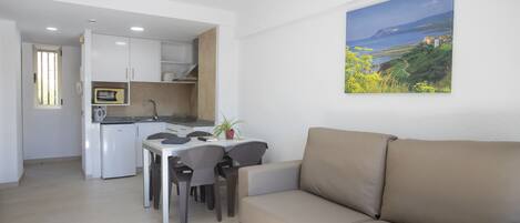 Um apartamento moderno com área de refeições, pequeno-almoço e uma grande janela com vista para a costa.