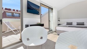 Quarto de hotel moderno com varanda, uma cama, uma TV e uma cadeira branca.