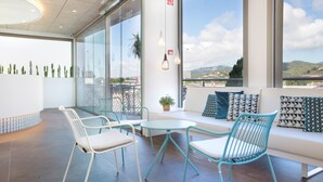Um interior moderno com área de estar, parede de vidro com vista e teto com iluminação embutida.