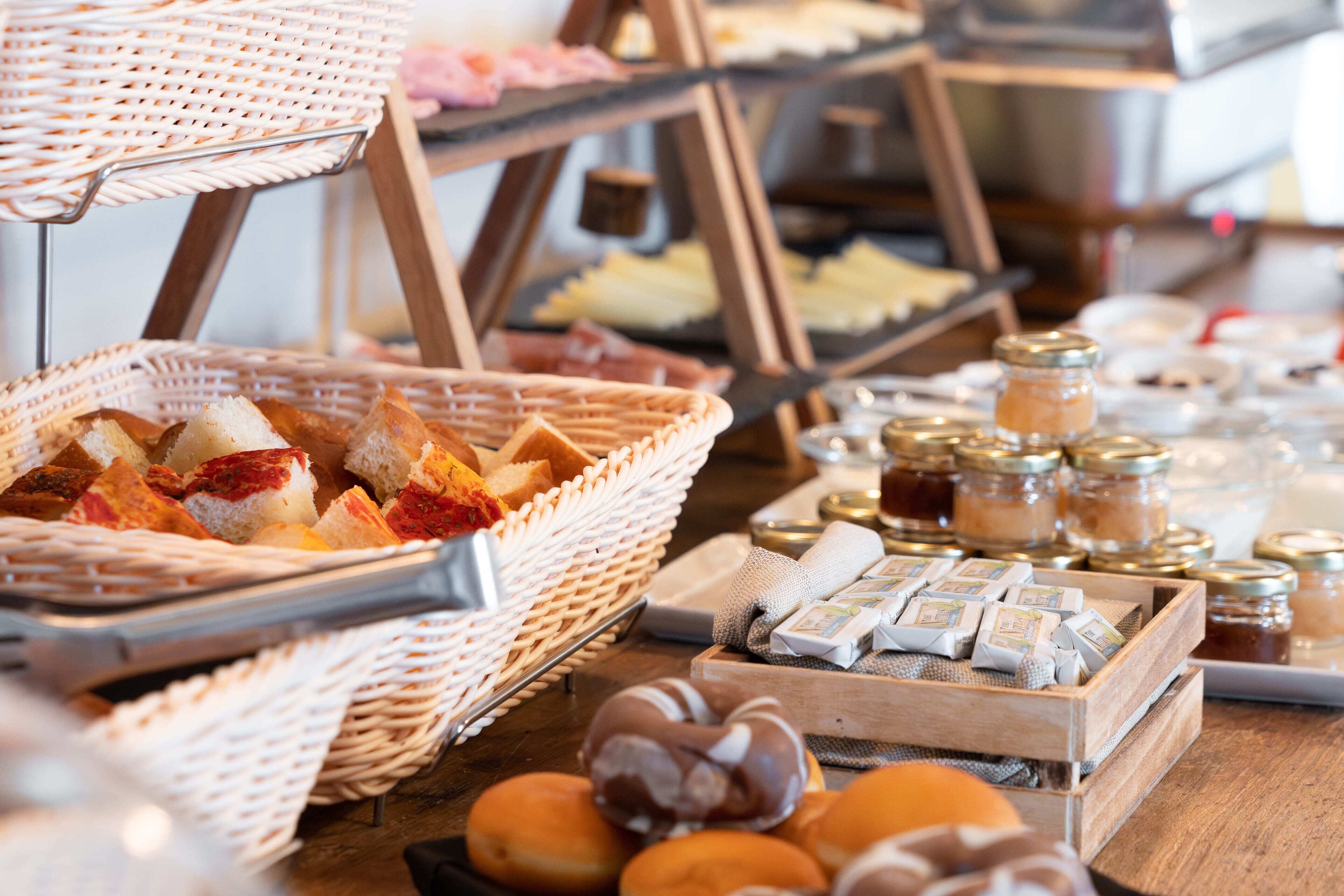 Buffet com diversos alimentos, incluindo pães, doces e acompanhamentos.