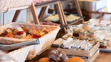 Buffet com diversos alimentos, incluindo pães, doces e acompanhamentos.