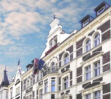 Um edifício histórico com vários andares, detalhes arquitetônicos elaborados e uma varanda imponente.