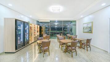 Um espaço interno amplo com piso lustroso, mobiliário de madeira e parede de vidro com vista para o exterior.