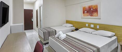 Quarto de hotel com duas camas, uma televisão, uma cabeceira de madeira e um quadro na parede.