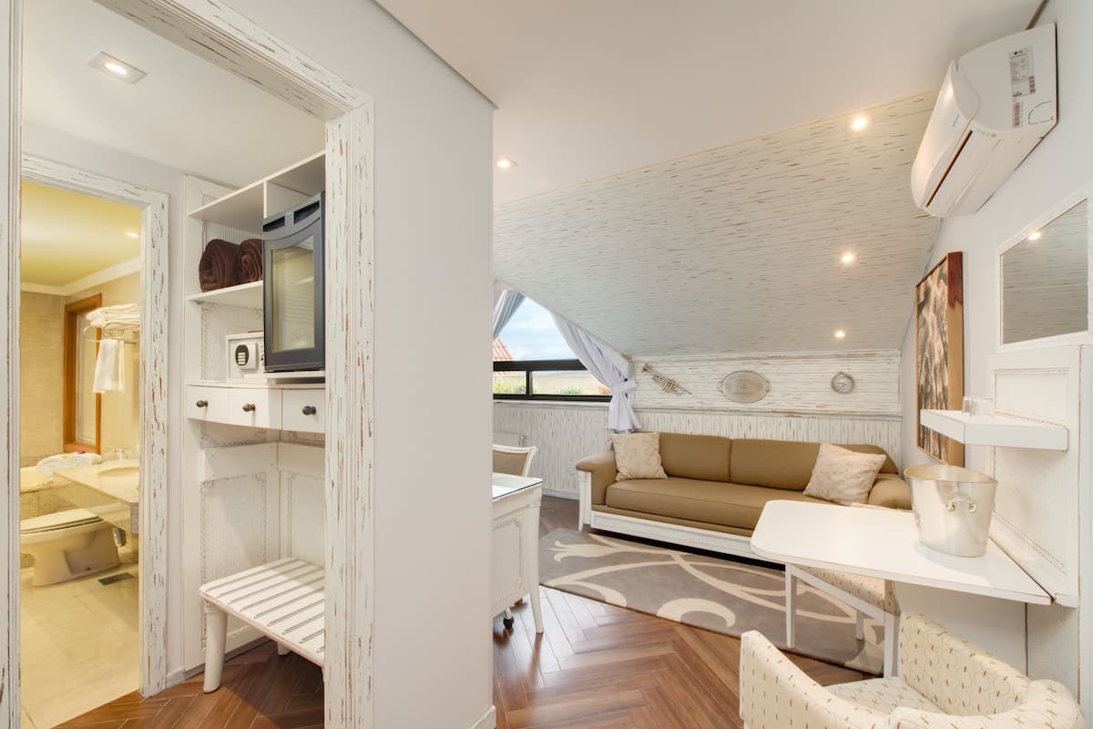 Quarto compacto e bem iluminado, com cozinha compacta, sofá e área de refeições.