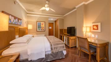 Quarto de hotel com cama, escrivaninha, televisão e obras de arte nas paredes.