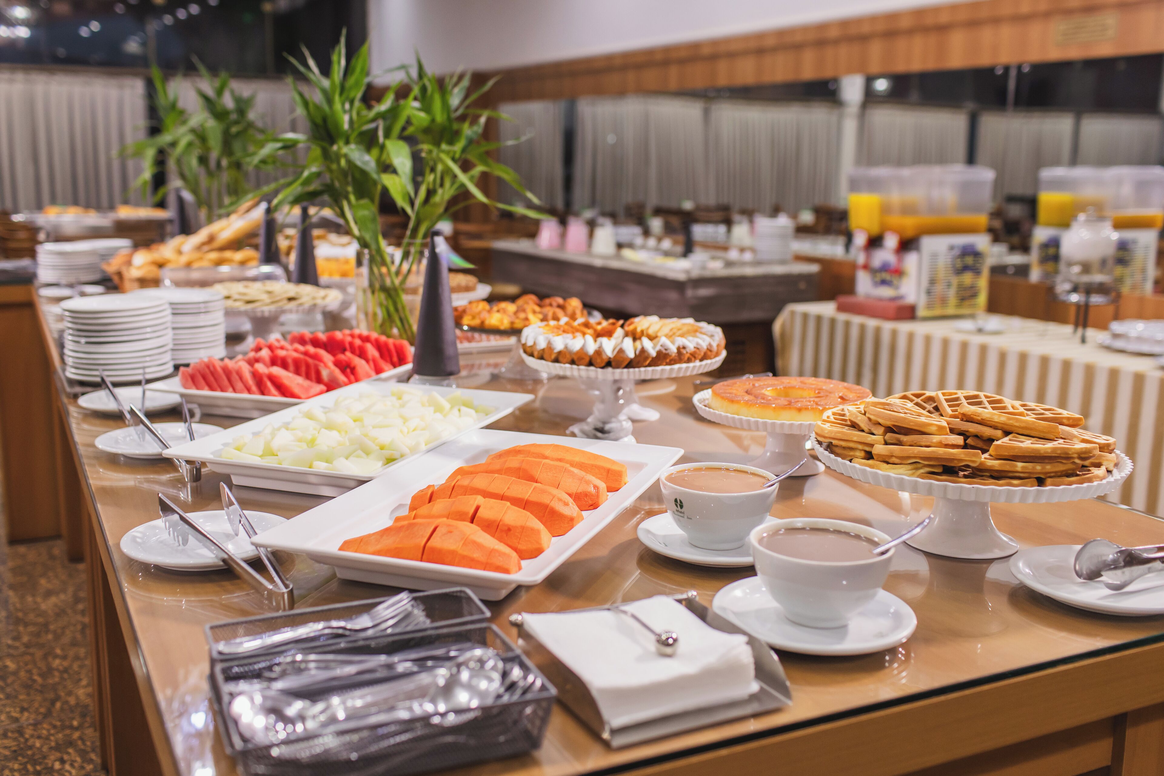 Buffet com diversos alimentos, incluindo fatias de laranja, waffles e outras opções.