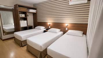 Quarto de hotel com duas camas de solteiro, um guarda-roupa, um espelho e parede listrada.