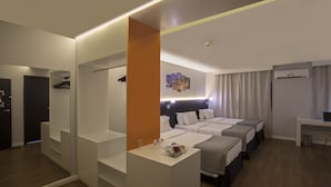 Quarto de hotel com duas camas, uma escrivaninha e um pequeno espaço para sentar.