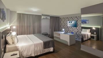Quarto de hotel com cama, mesa de cabeceira, escrivaninha e espelho.