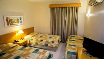 Quarto de hotel com duas camas, uma televisão, um abajur e um aparelho de ar condicionado.