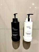 Dois frascos de shampoo sobre uma superfície espelhada.
