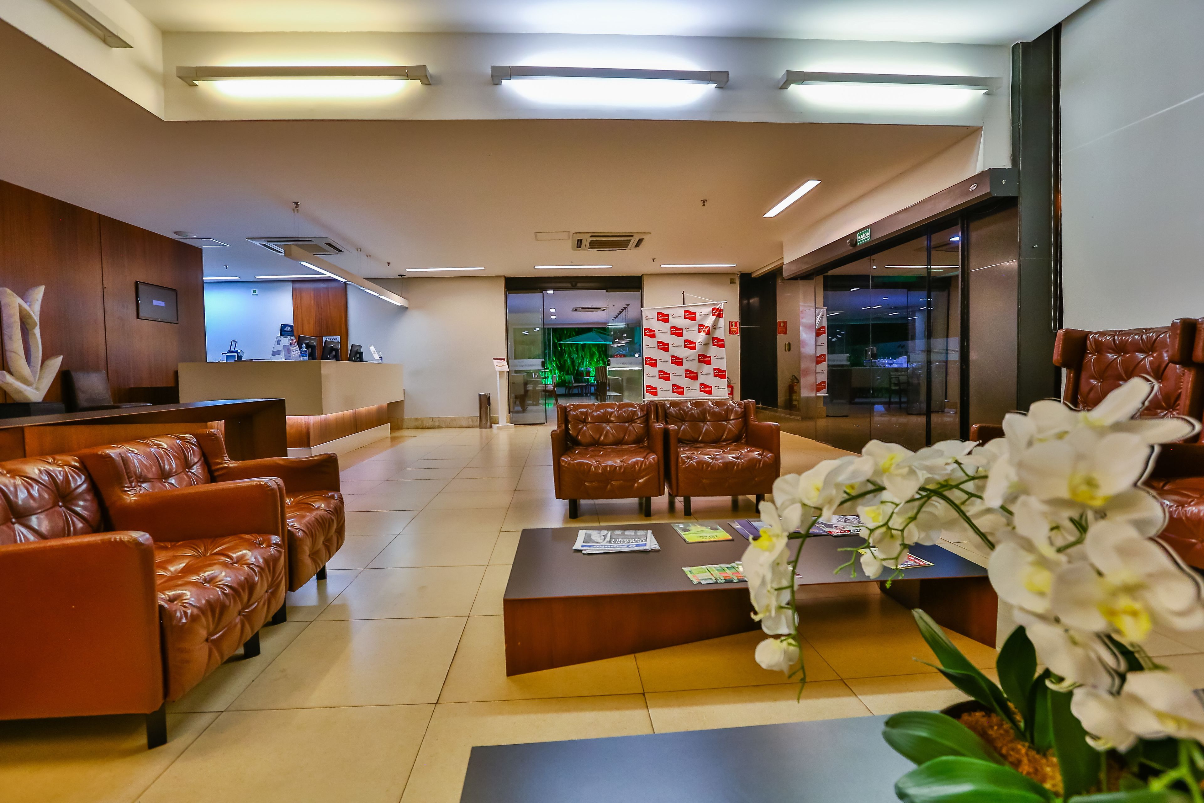 Um hall com sofás de couro, um balcão de recepção e uma máquina de café.