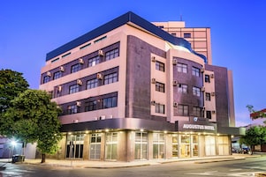 Um hotel com vários andares, fachada moderna, janelas amplas e uma sinalização chamativa para 'AUGUSTUS HOTEL'.