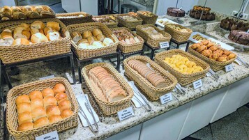 Vitrine de padaria com diversos pães e doces.